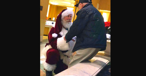 Santa Kneels In Front Of Elderly Man As Woman Hears Him Say Something ...